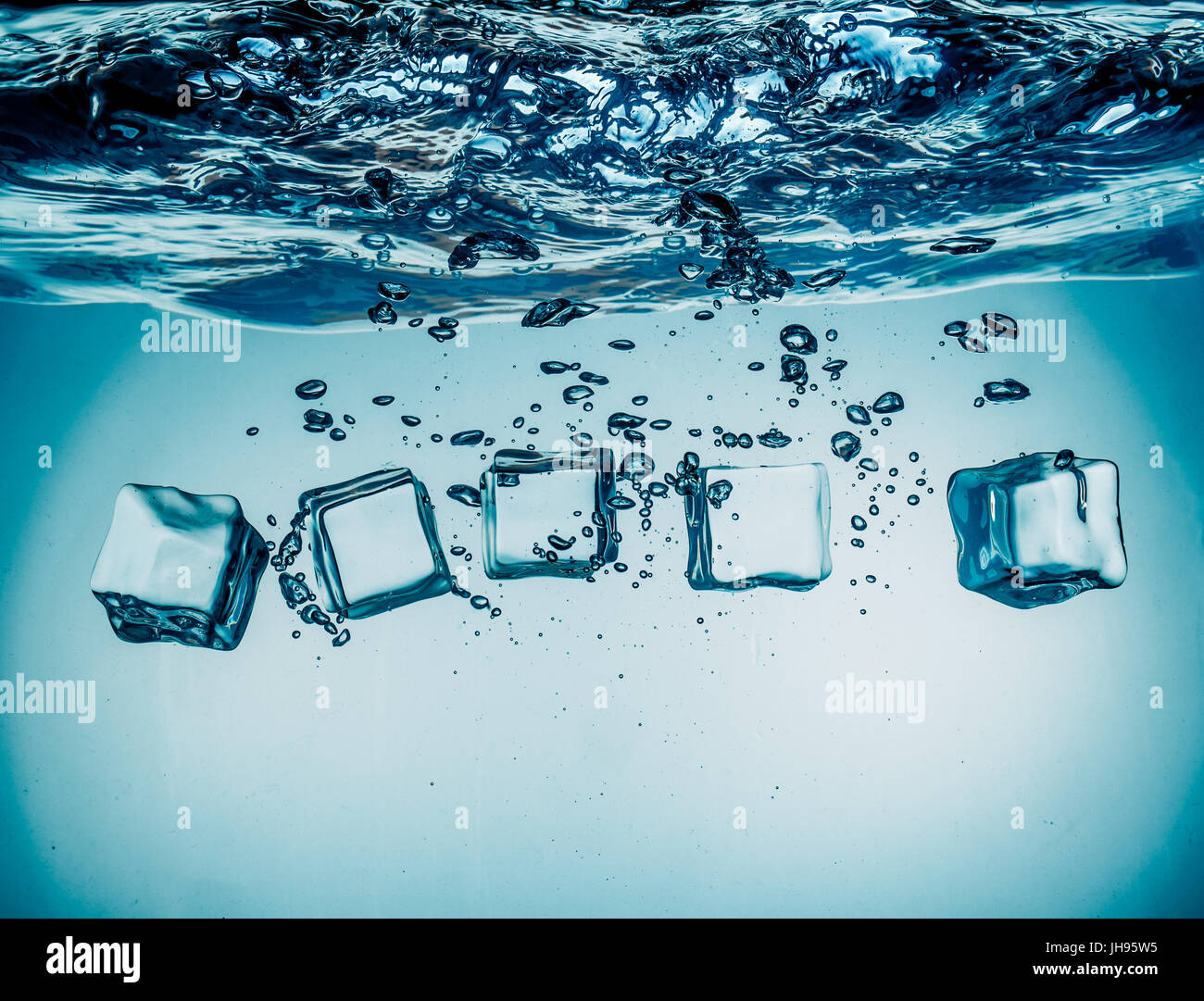 Ice cubes falling into the water sinking to the bottom. Abstract ...