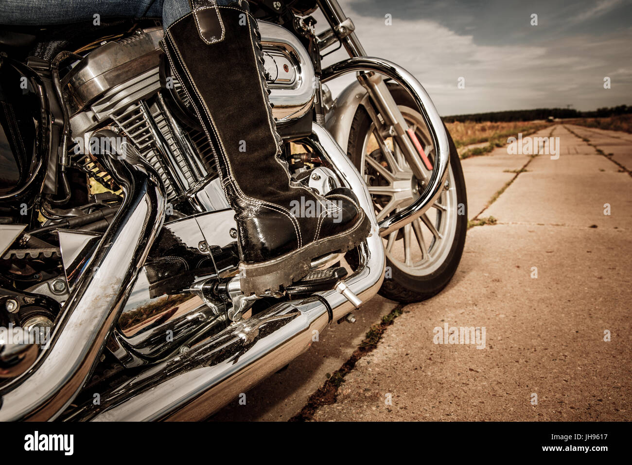 Biker girl riding on a motorcycle. Bottom view of the legs in leather ...