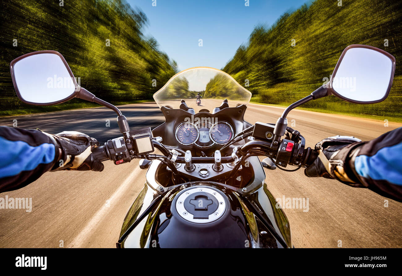 Biker driving a motorcycle rides along the asphalt road. First-person ...