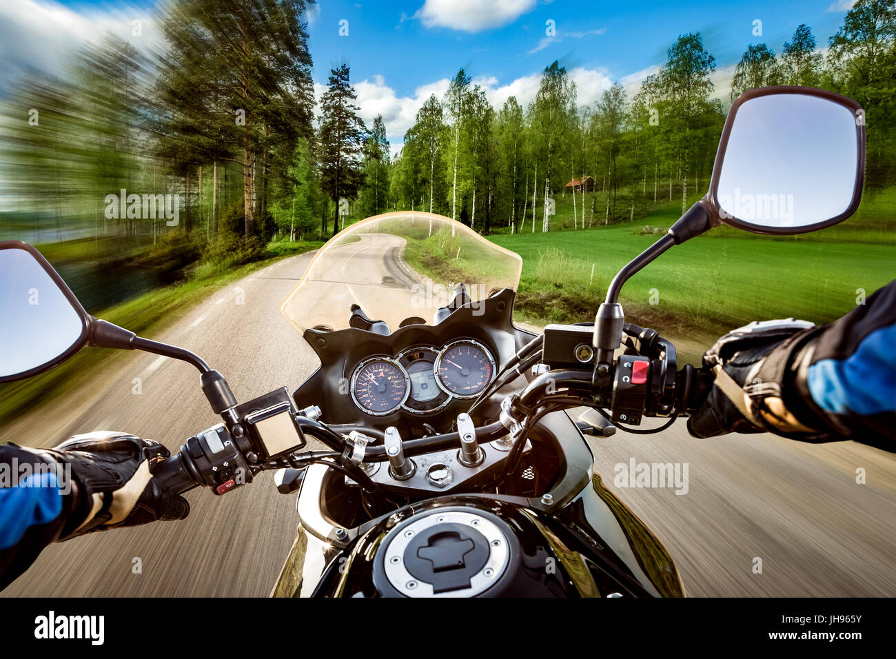 Biker driving a motorcycle rides along the asphalt road. First-person ...