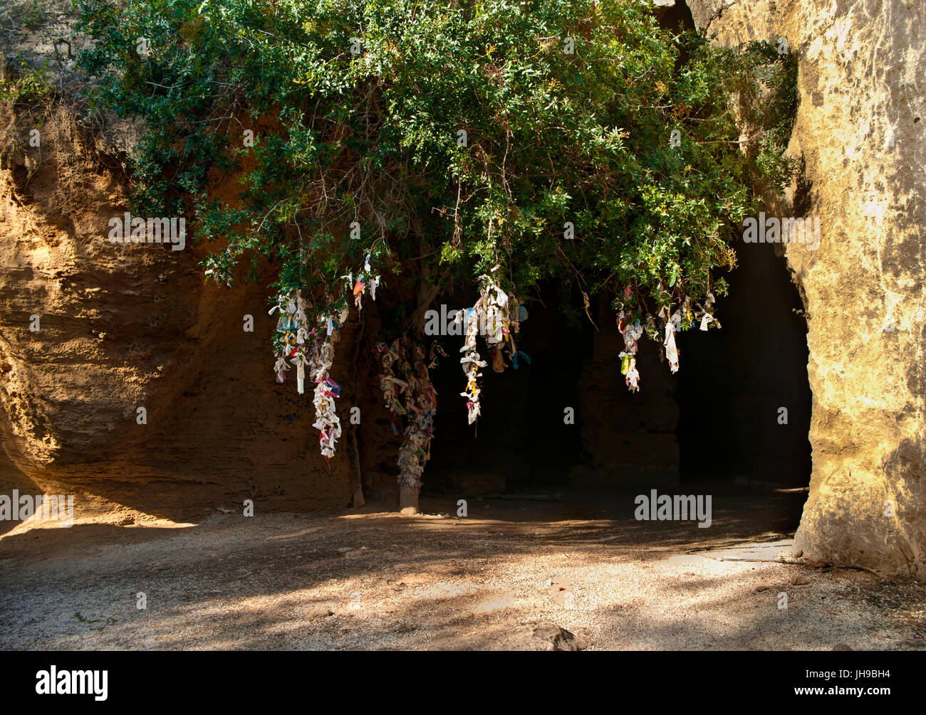 Agia Solomoni catacomb entrance with pistachio tree and tied pieces of ...