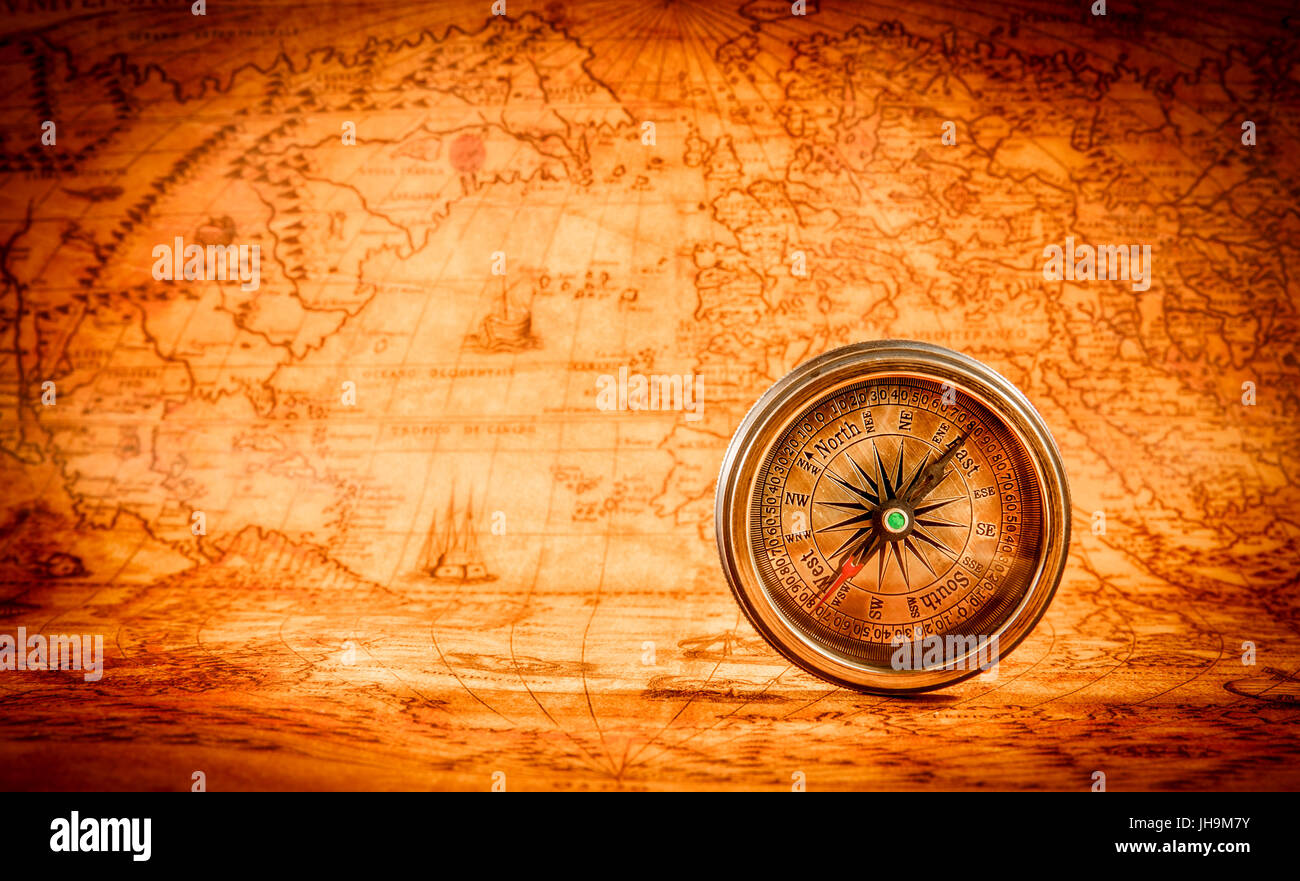 Vintage still life. Vintage compass lies on an ancient world map in ...