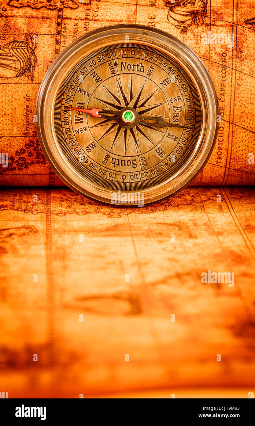 Vintage still life. Vintage compass lies on an ancient world map in ...