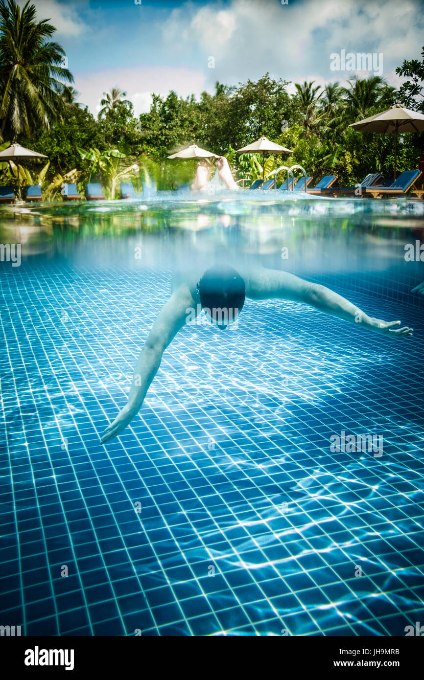 Man dives into a swimming pool views over the water and under water ...