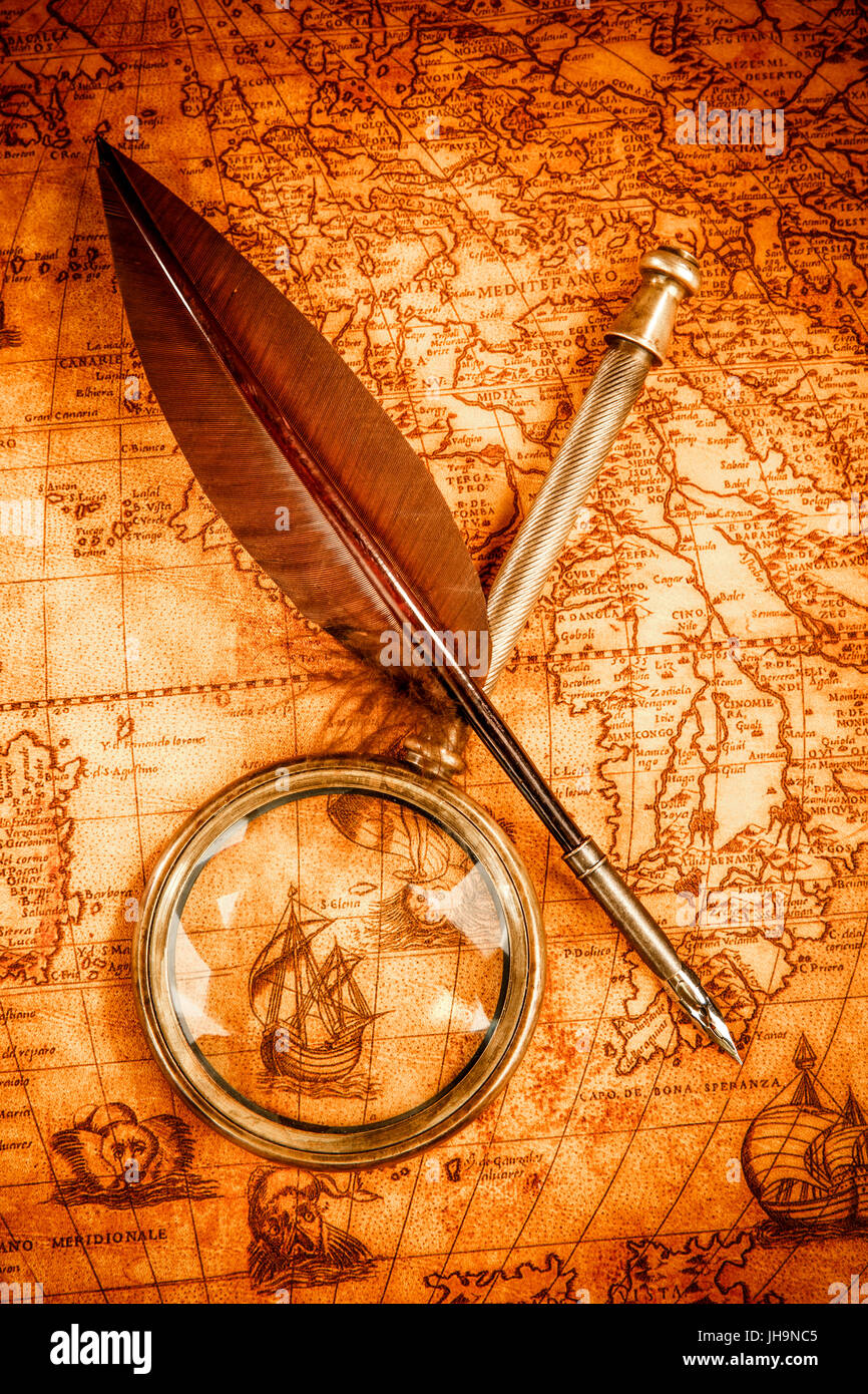 Vintage magnifying glass and quill pen on an old ancient map in 1565 ...
