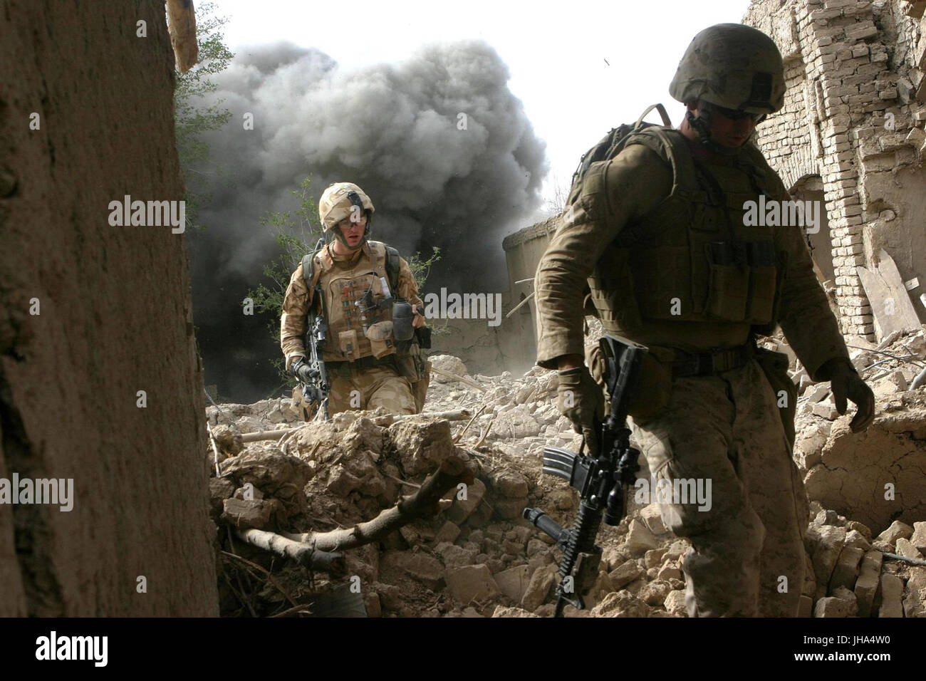 U.S. and Estonian soldiers walk over rubble as a controlled detonation ...