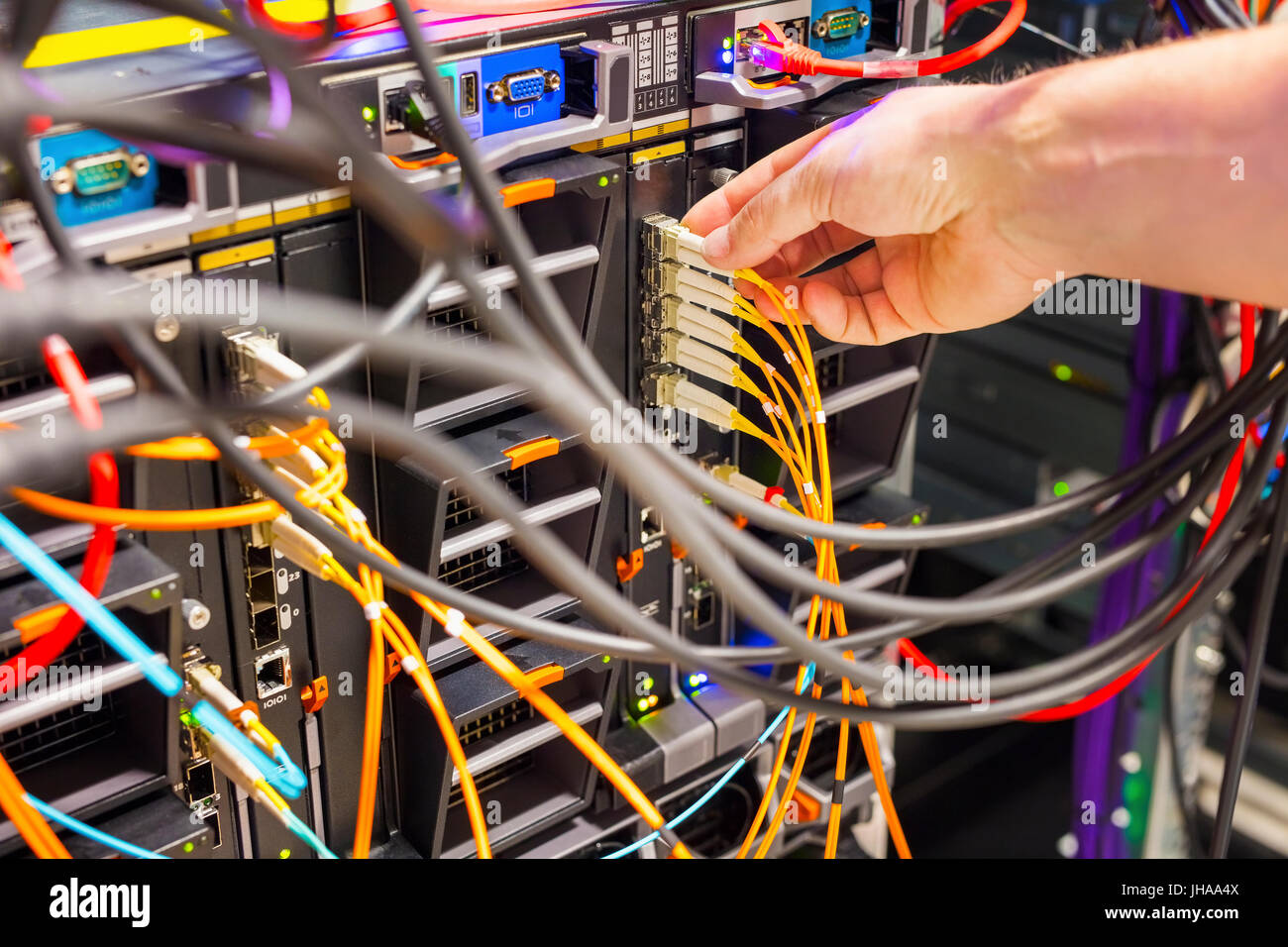 Closeup of IT technician's hand plugging fiber channel cable into ...