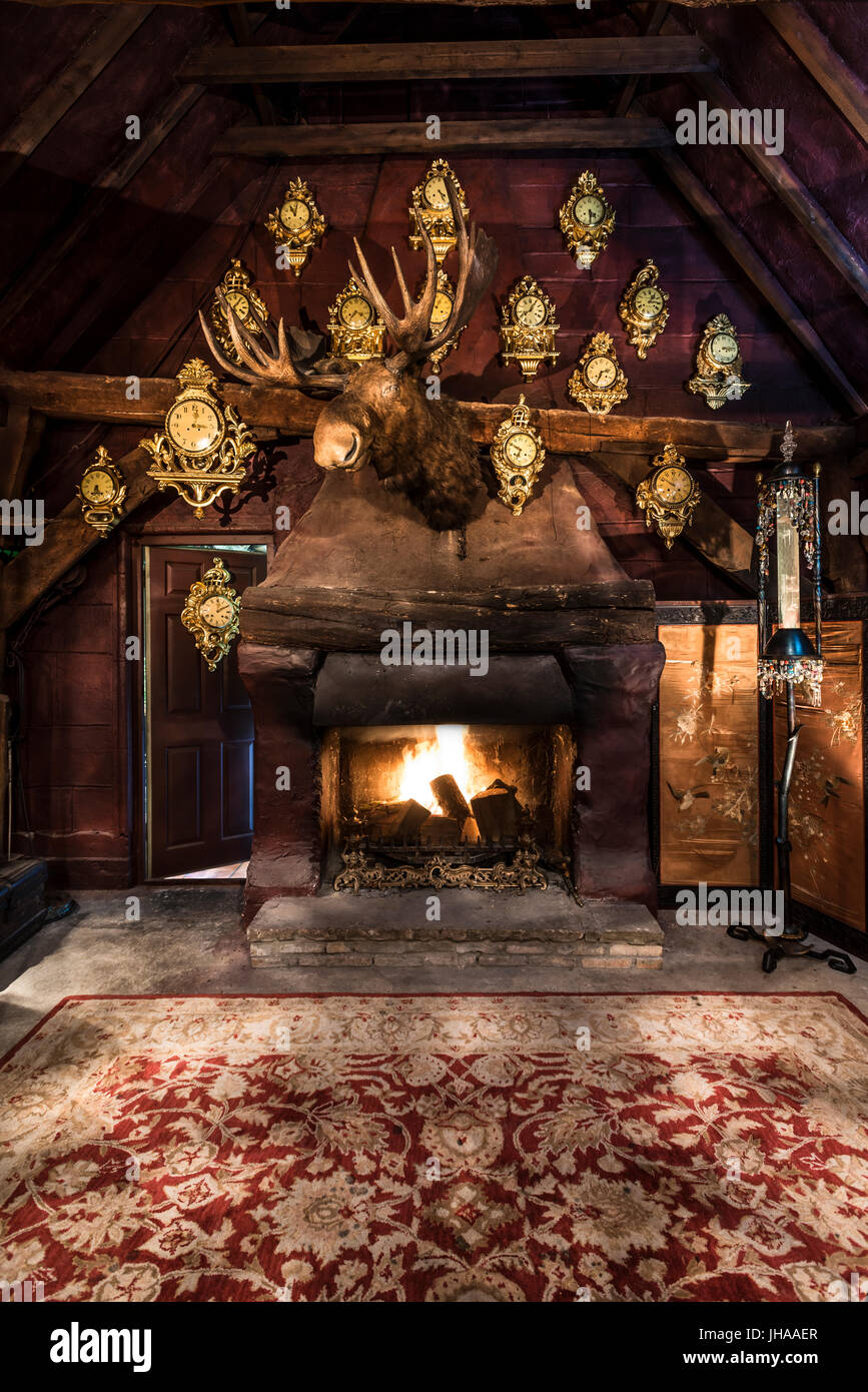 Clocks and stag head over lit fireplace Stock Photo - Alamy