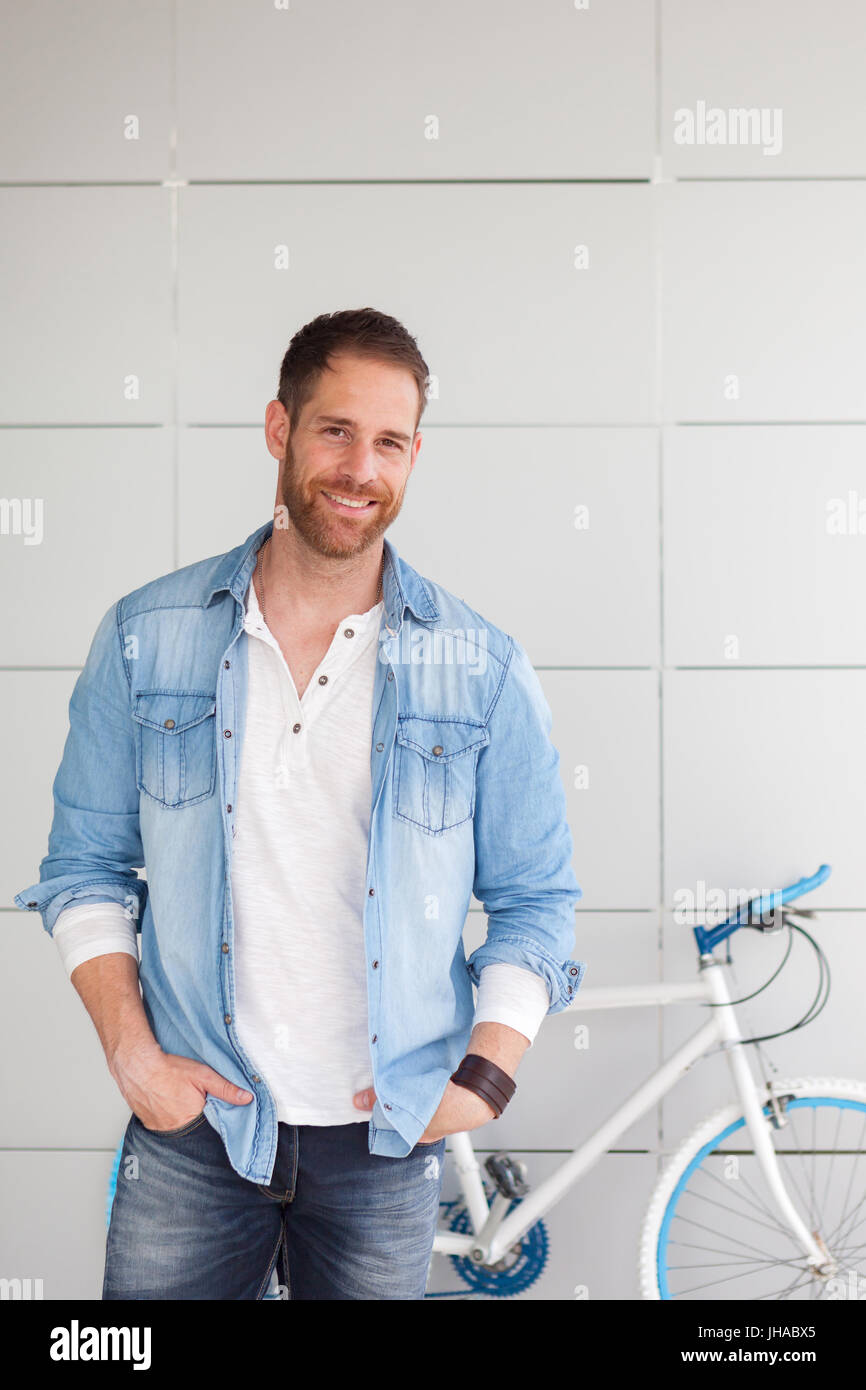 Pensive guy with denim shirt and beard next to his bike Stock Photo - Alamy