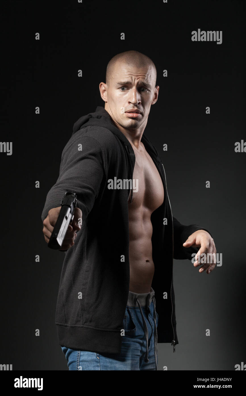 scared man shooting gun isolated on dark background Stock Photo - Alamy