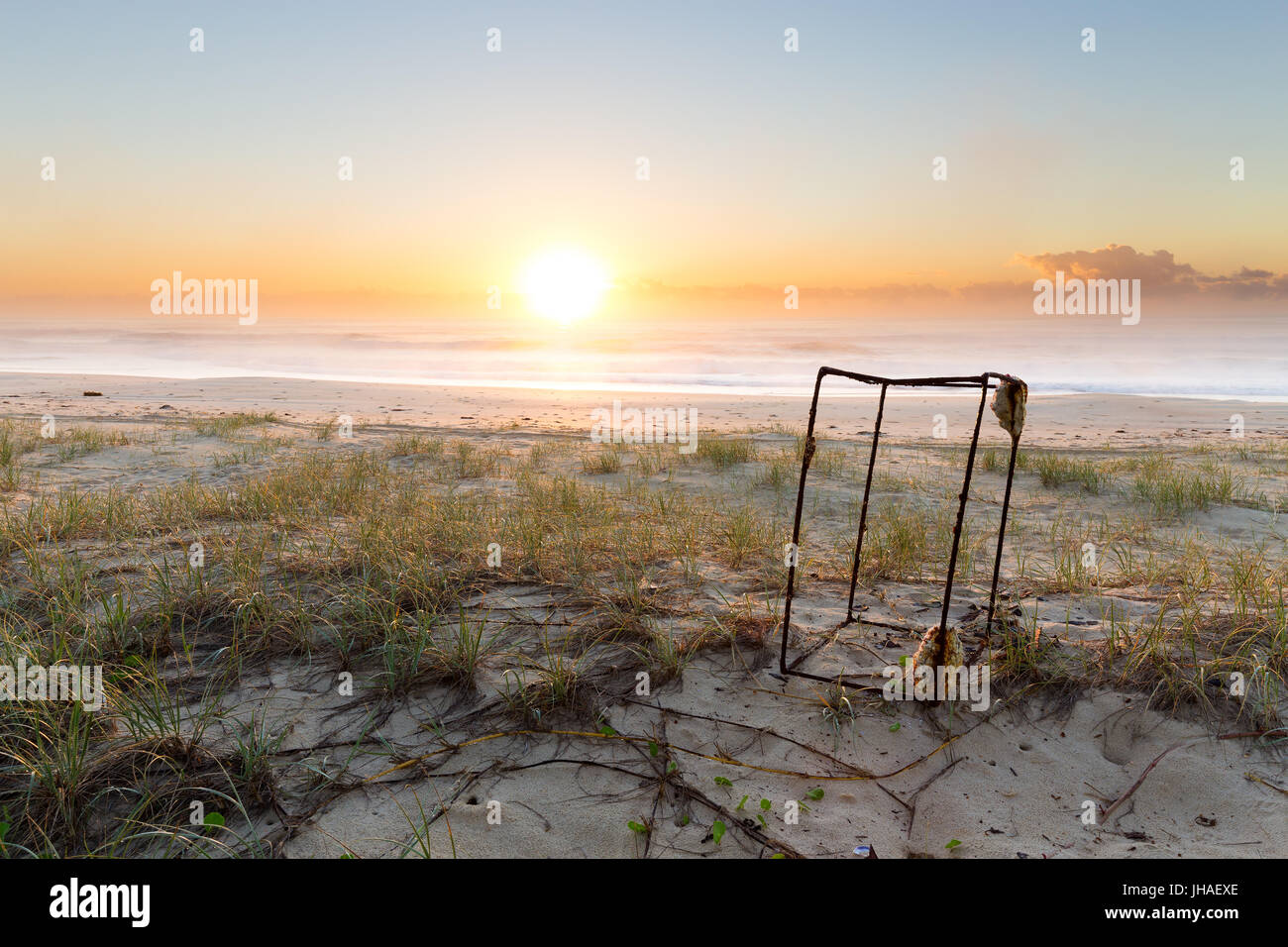 A rusted piece of rectangular ocean litter sits on the beach as the ...