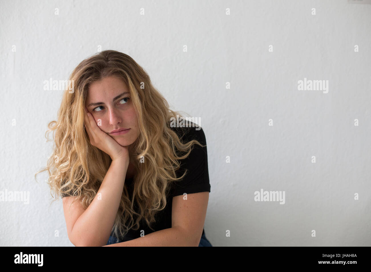Young, blonde, caucasian woman annoyed while sitting down. Looking off ...