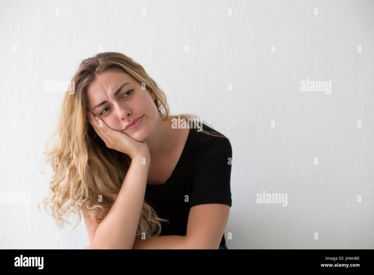 Young, blonde, caucasian woman annoyed while sitting down. Looking off ...