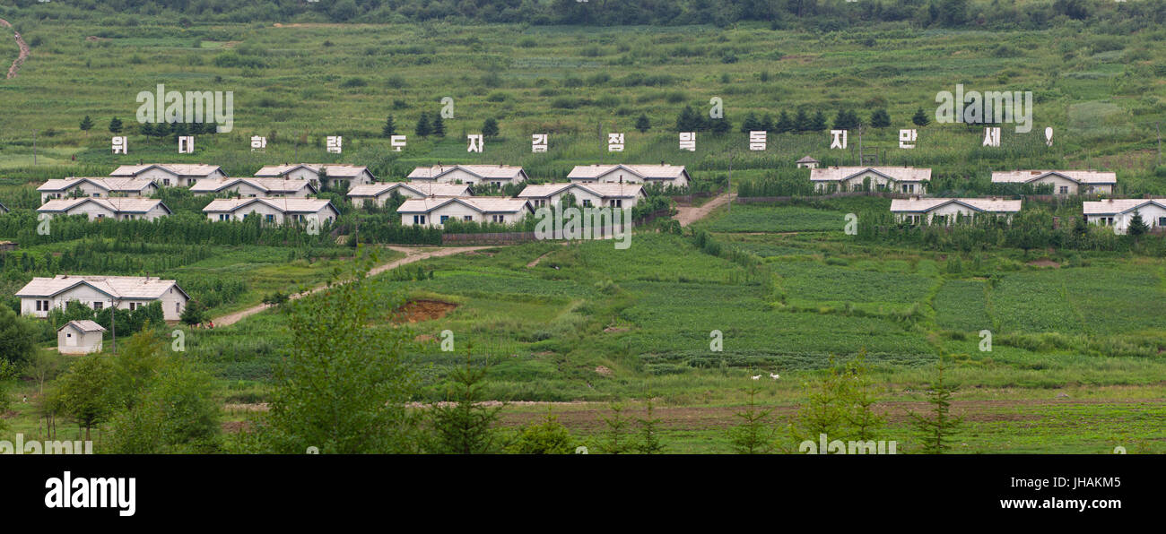 Farms and village buildings, with political slogan on hillside behind ...
