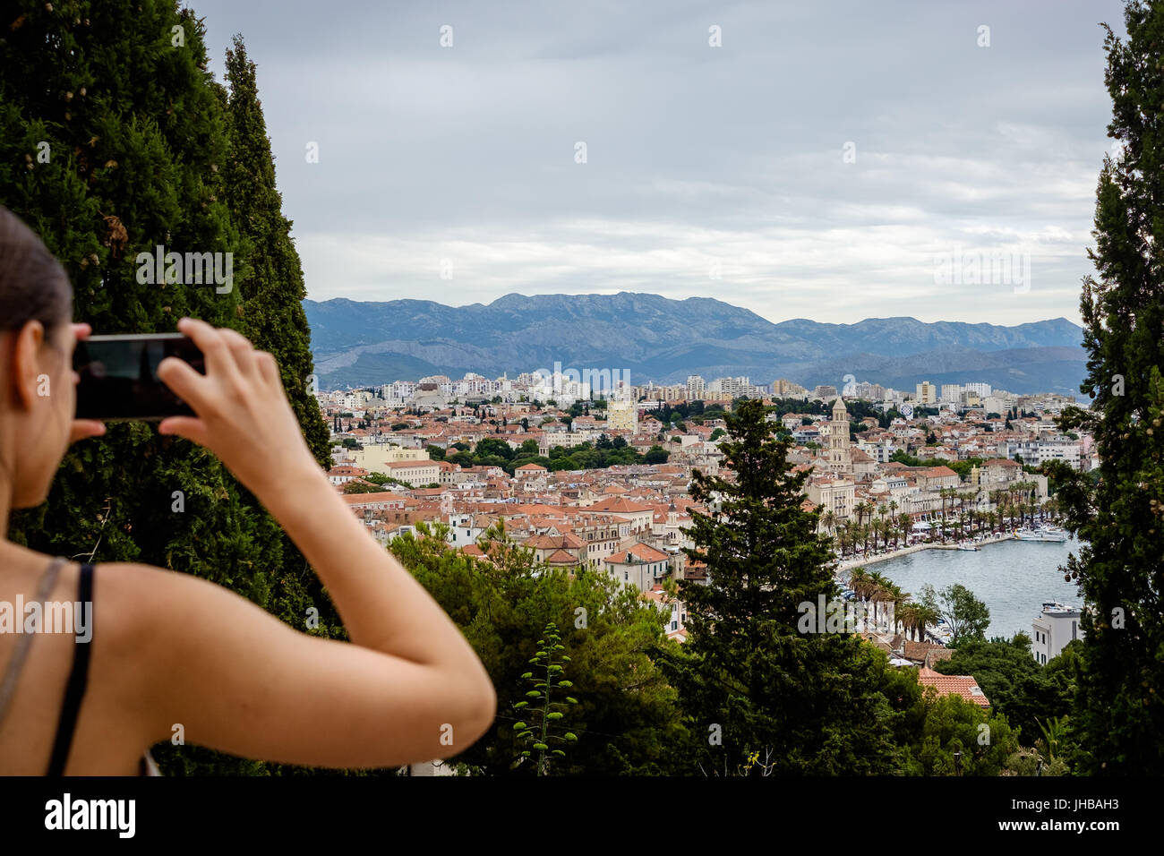 A young woman taking a photo of Split from above the city in Park ...