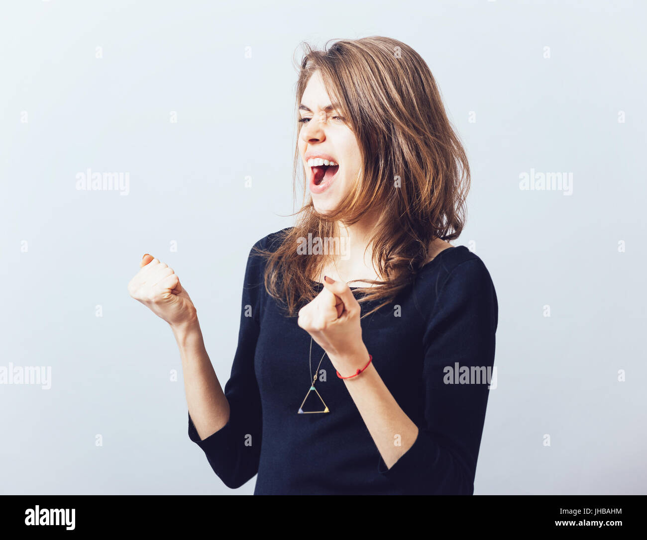 Excited young woman with fists up Stock Photo - Alamy