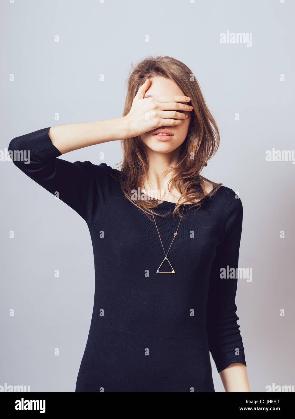 woman covering her eyes isolated on a gray background Stock Photo - Alamy