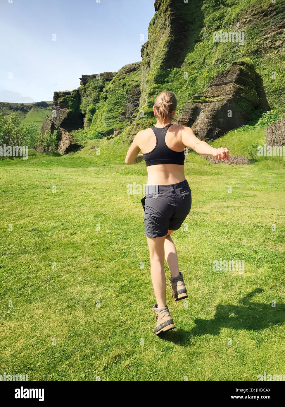 Young female jogging in the wilderness on a sunny day, vertical outdoor ...