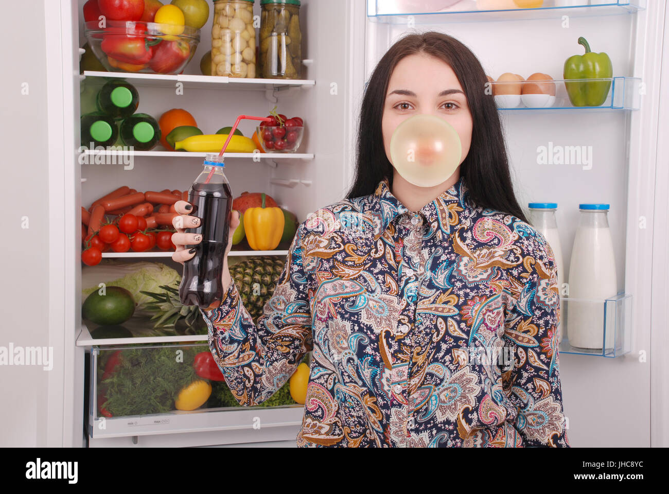 Young girl holding cola and making a big bubble with a chewing gum on ...