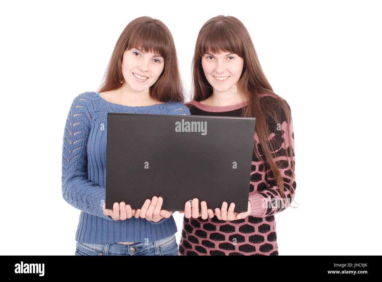 Portrait of two twins sisters with laptop on white background Stock ...