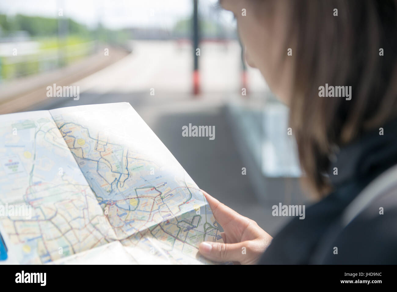 Woman with watching a map in a train station Stock Photo - Alamy