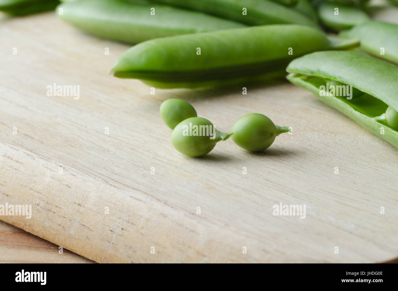 Food preparation scene. Three freshly picked peas with stalks on a ...