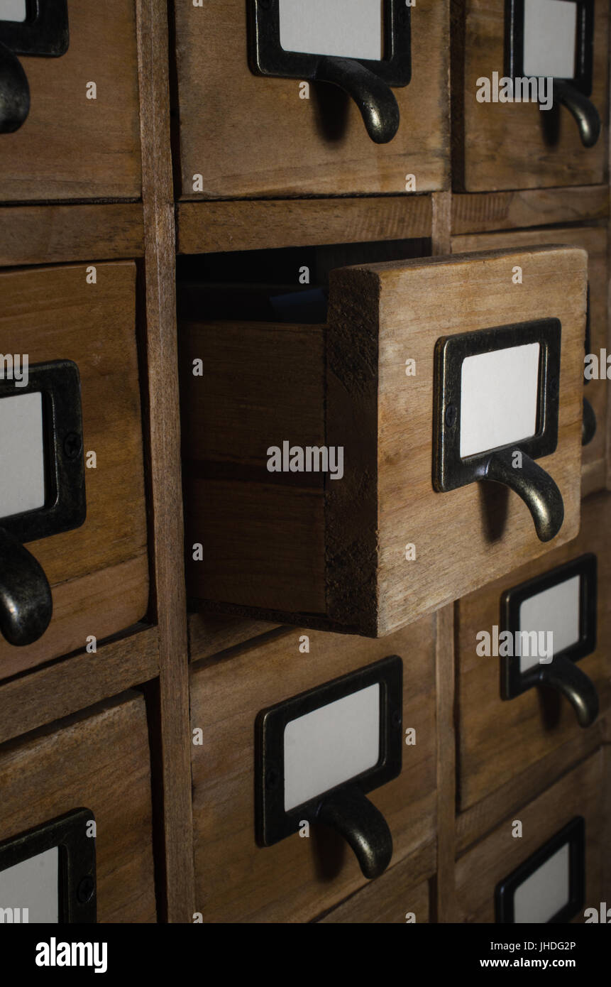 Angled side view of card index drawers lit by a bright light in a dark ...