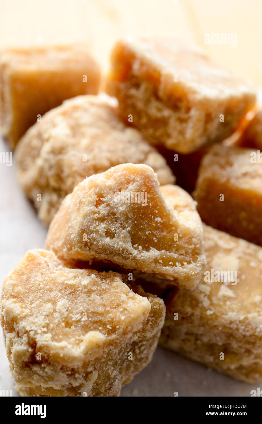 Close up of light brown broken fudge pieces grouped on parchment paper ...