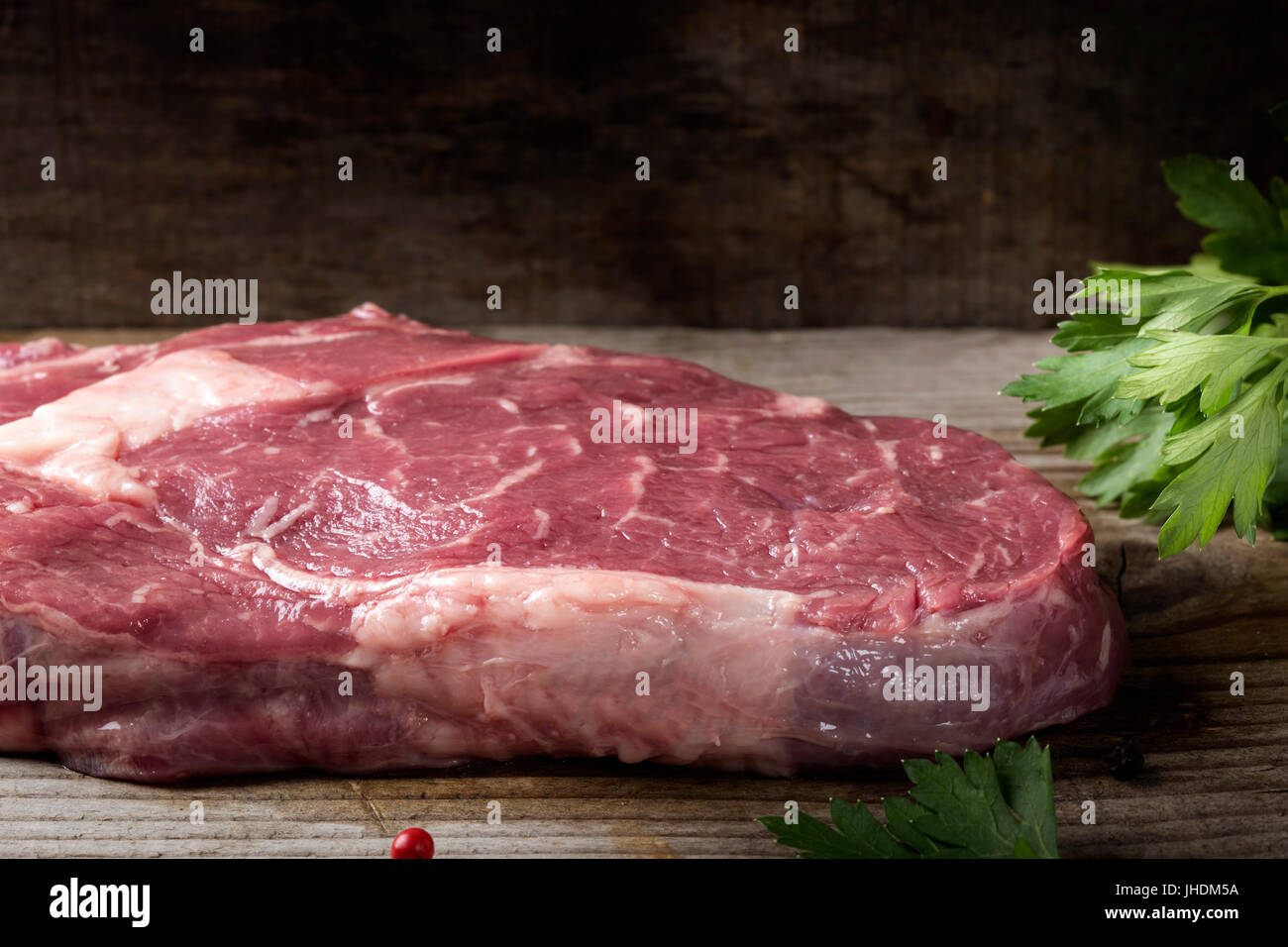 Raw Rib Eye Steak with parsley on wooden rustic background Stock Photo ...