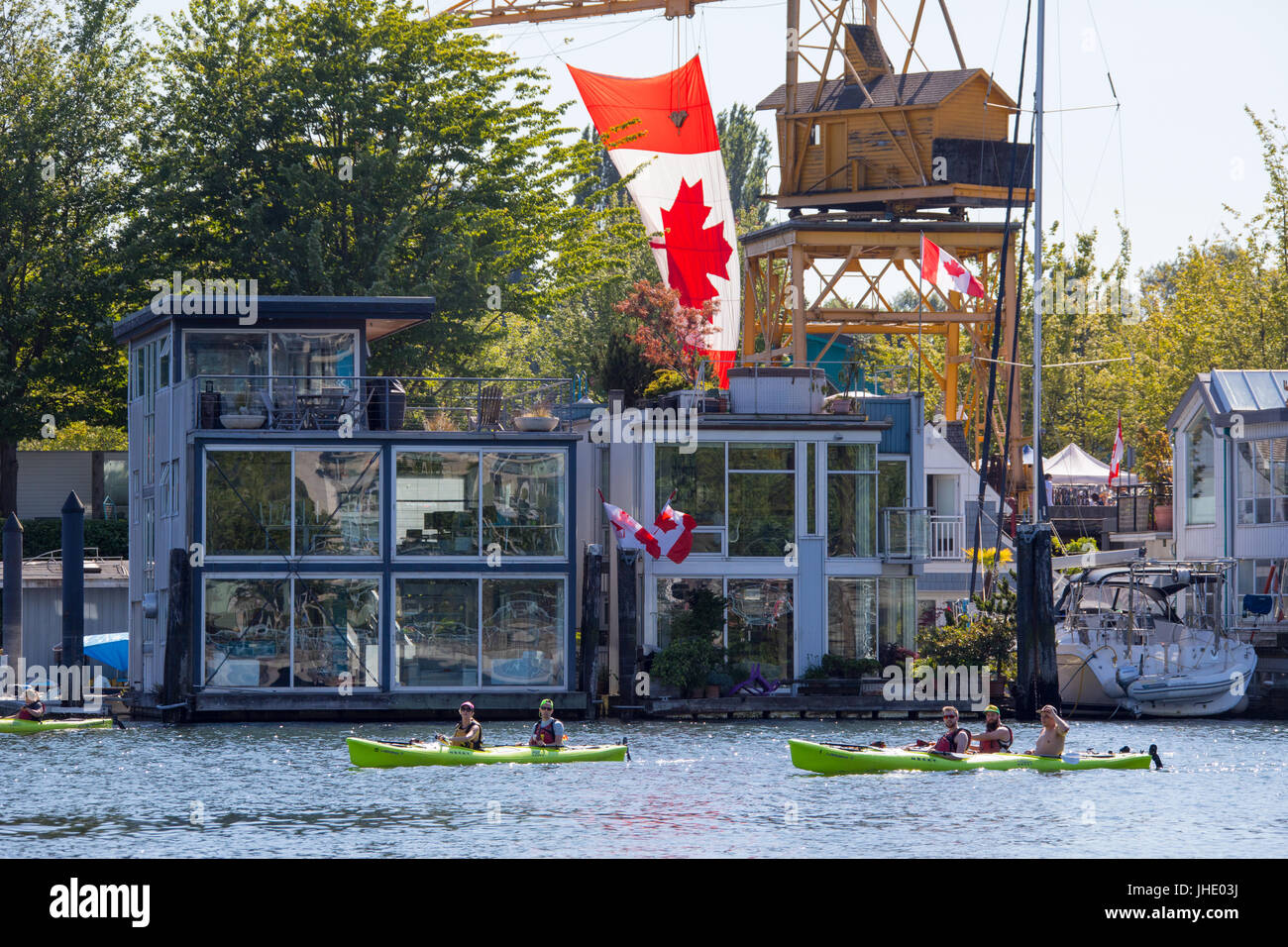 Kayaks row past waterfront homes on Granville Island, Vancouver, Canada ...