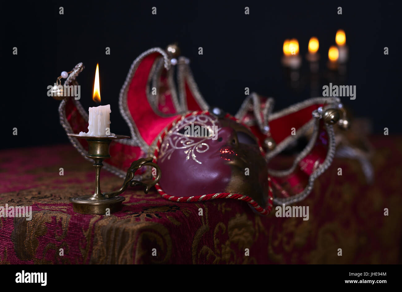 Candle in small brass candlestick and Venetian mask Stock Photo - Alamy