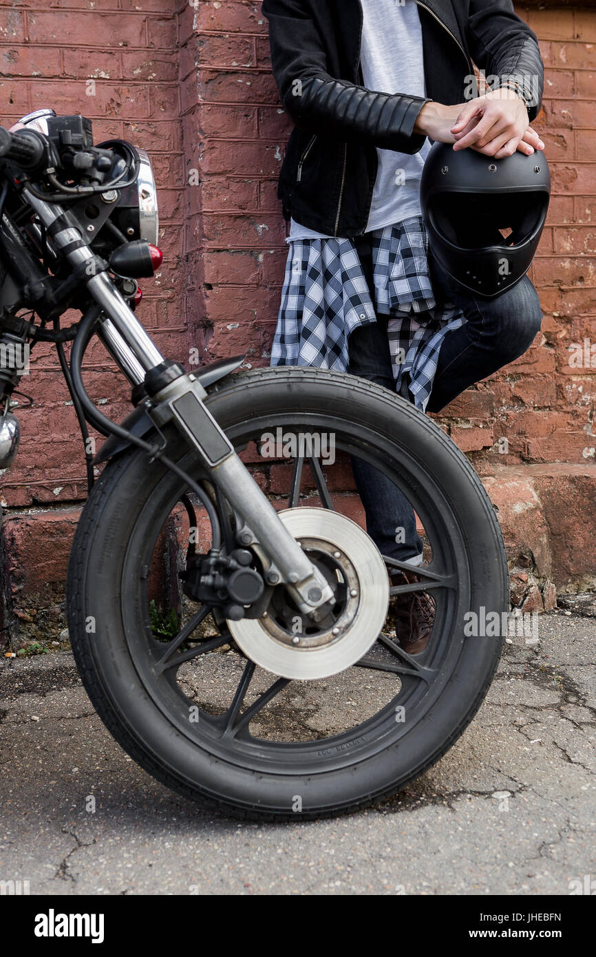 Closeup of a handsome rider biker guy hand with black helmet near brick ...