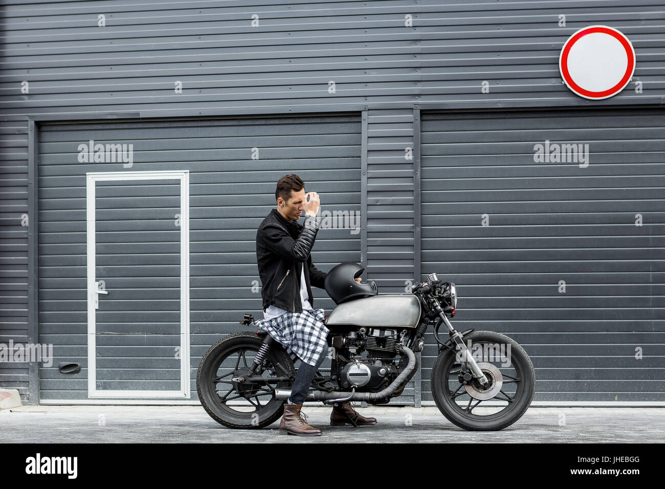 Handsome rider man biker correct hair after helmet sit on classic style ...