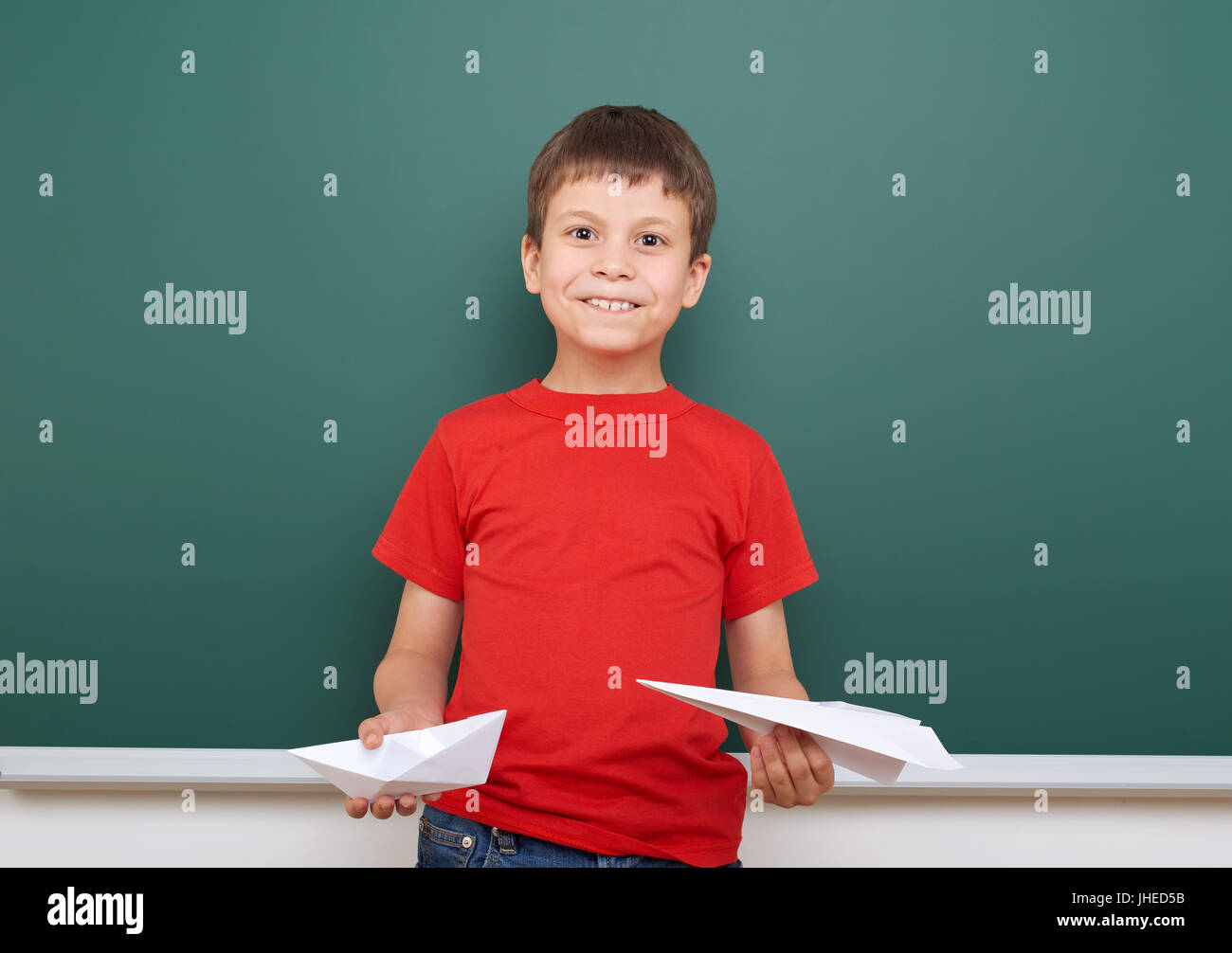 Schoolboy with paper plane play near a blackboard, empty space ...