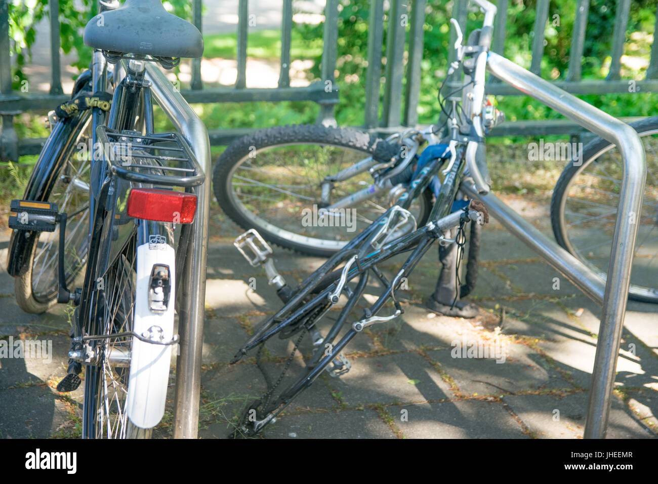 Bike chained to railings with a wheel missing Stock Photo - Alamy