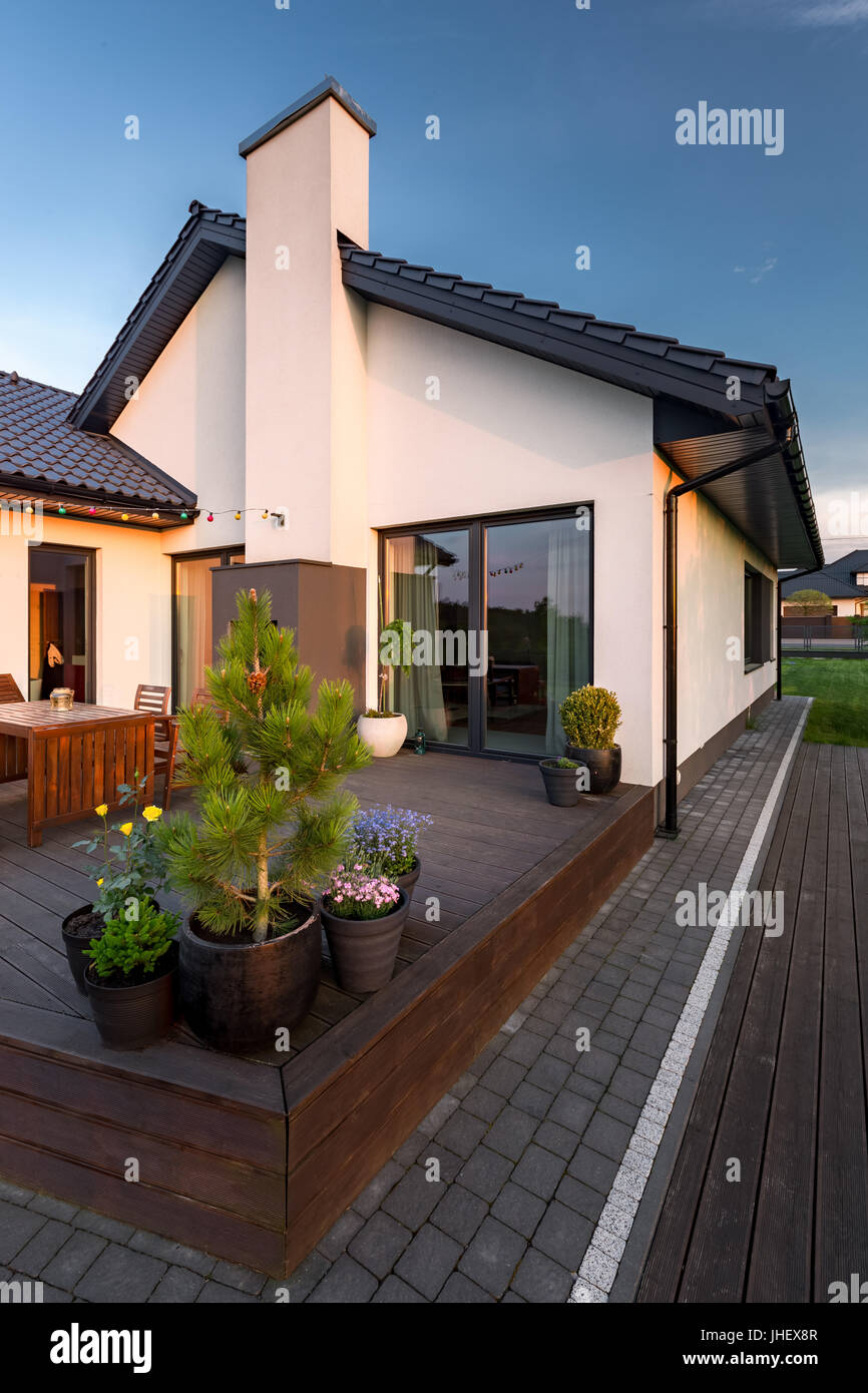 Exterior view of cozy family house with patio and decorative plants ...