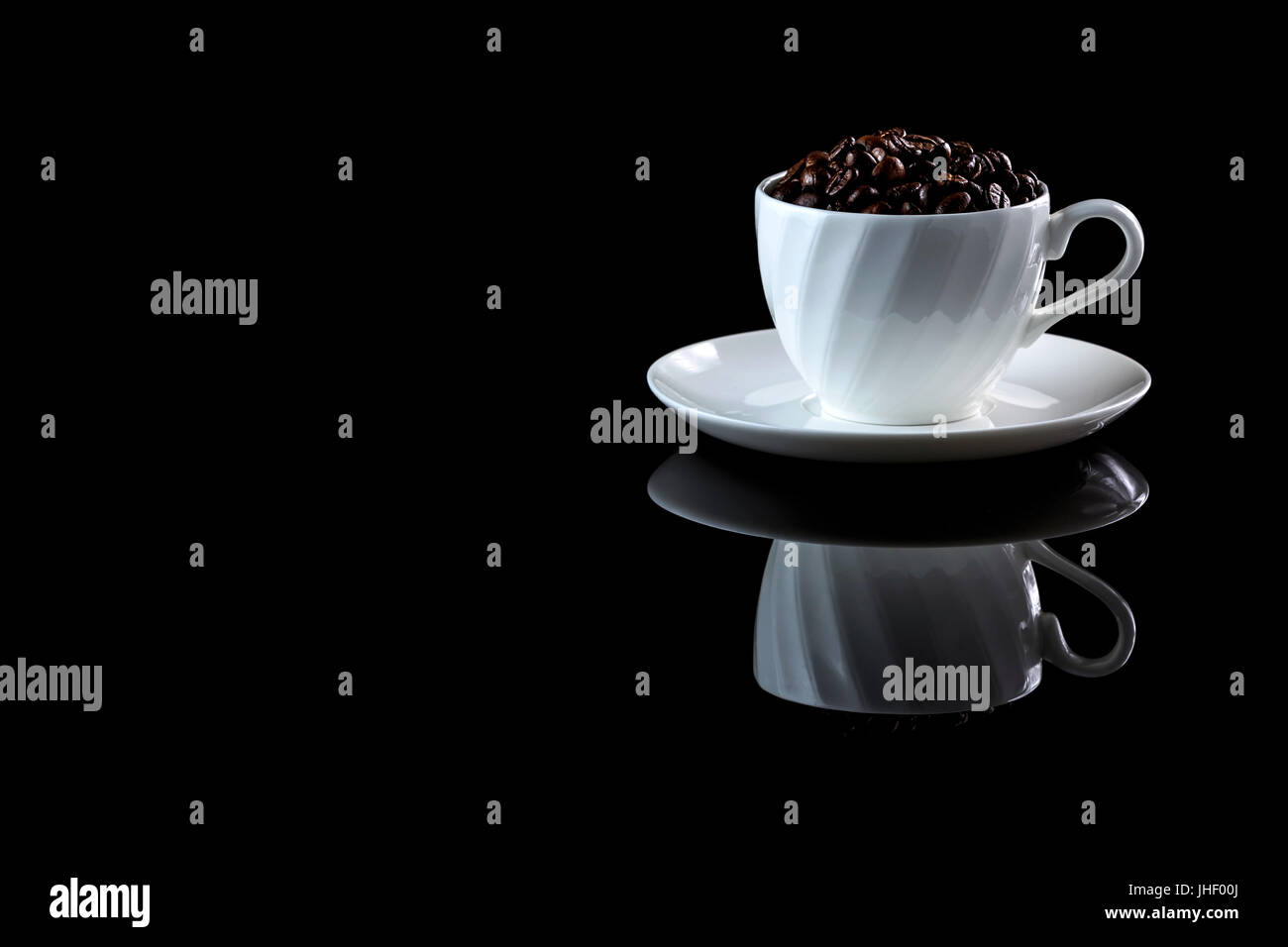 Cup with coffee beans on a black reflective background. Studio shot ...