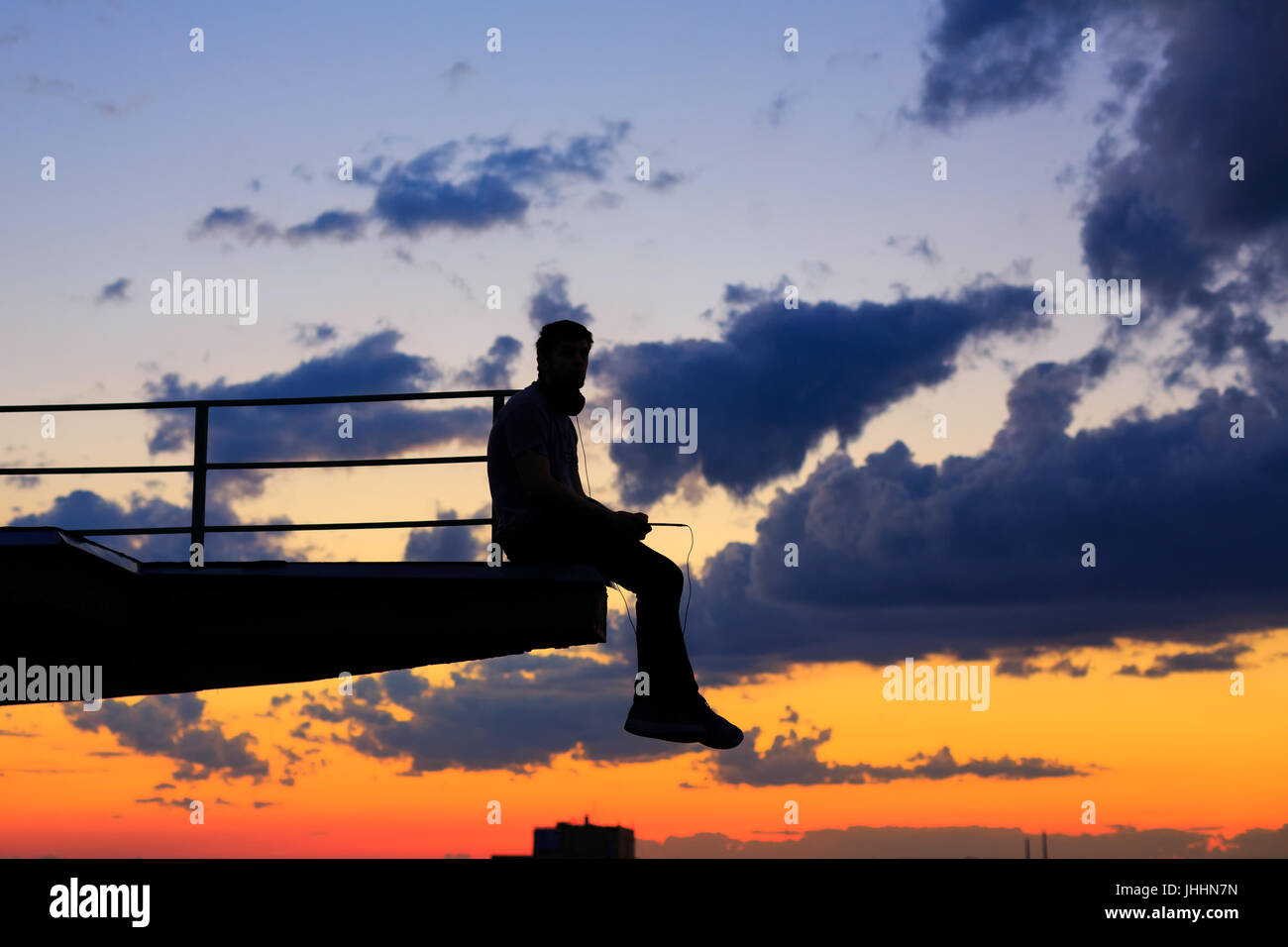 Silhouette of a man against background of clouds and golden sunset. He ...