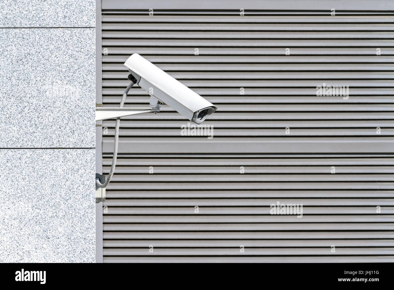 outdoor surveillance camera on facade of building against closed metal ...