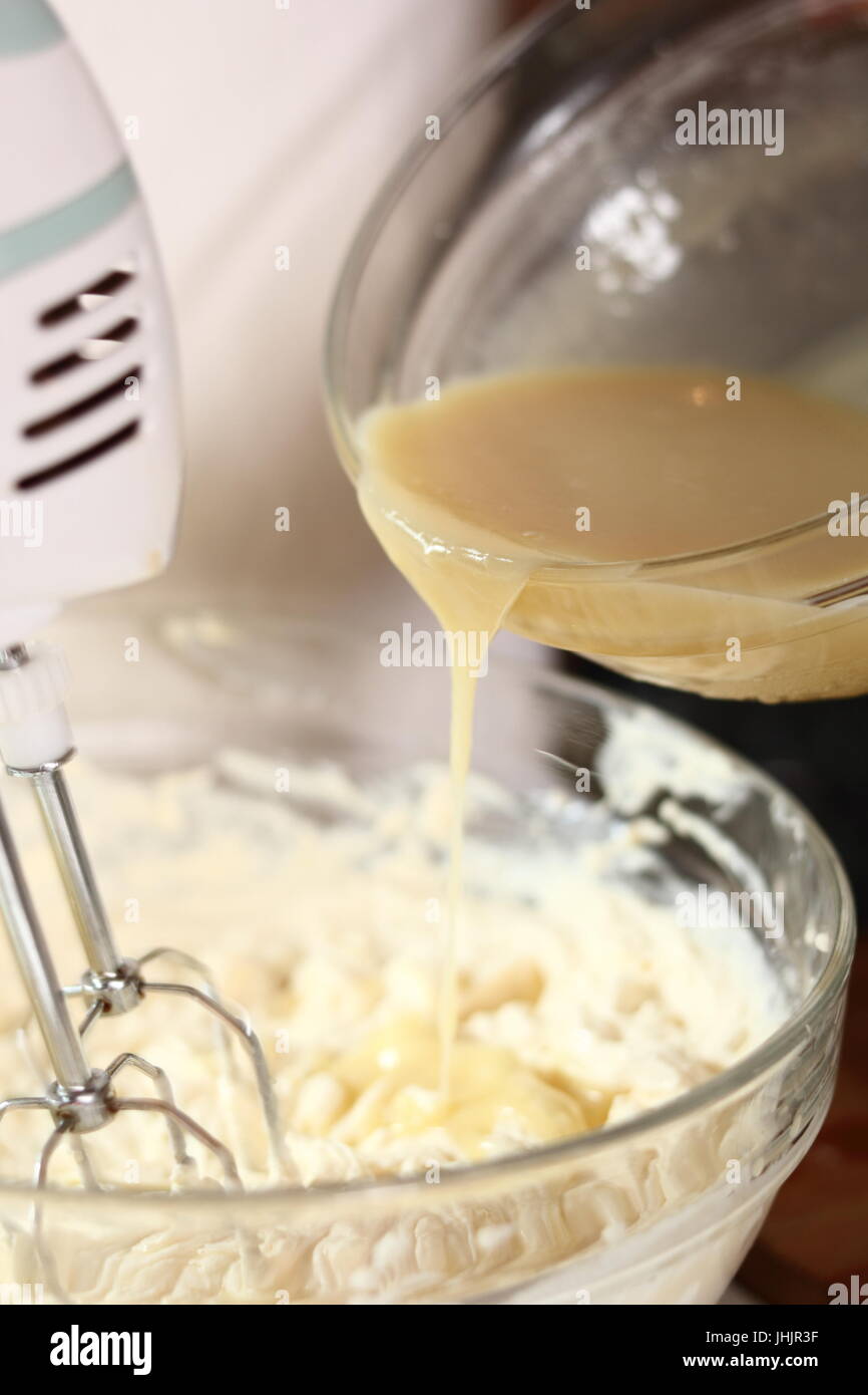 Pouring white chocolate and butter mixture into cheese filling. Making ...
