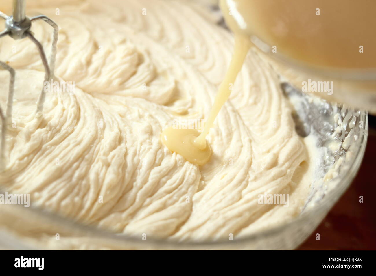 Pouring white chocolate and butter mixture into cheese filling. Making ...