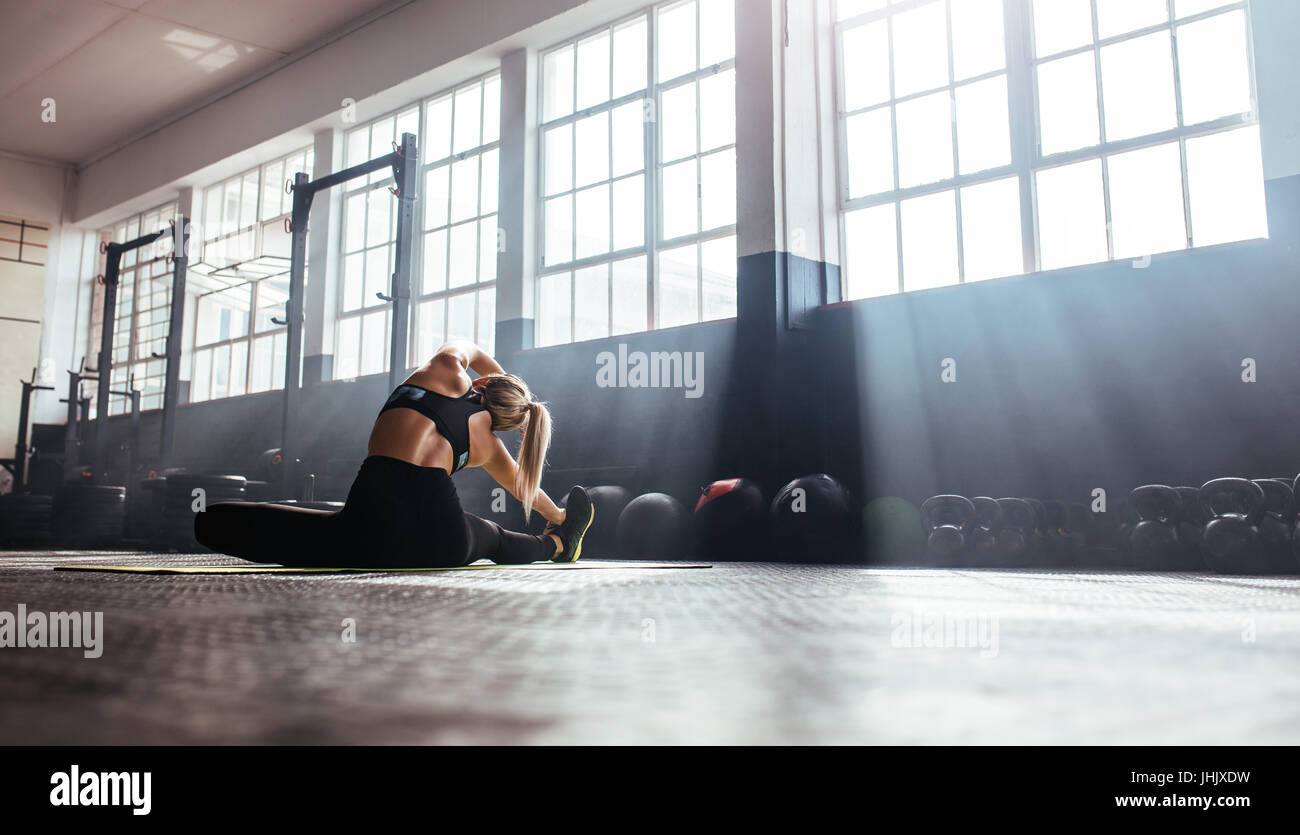 Young woman working out in gym. Back view of woman doing stretching ...