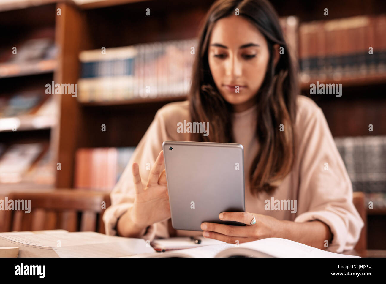 University female student using digital tablet in library. Young female ...