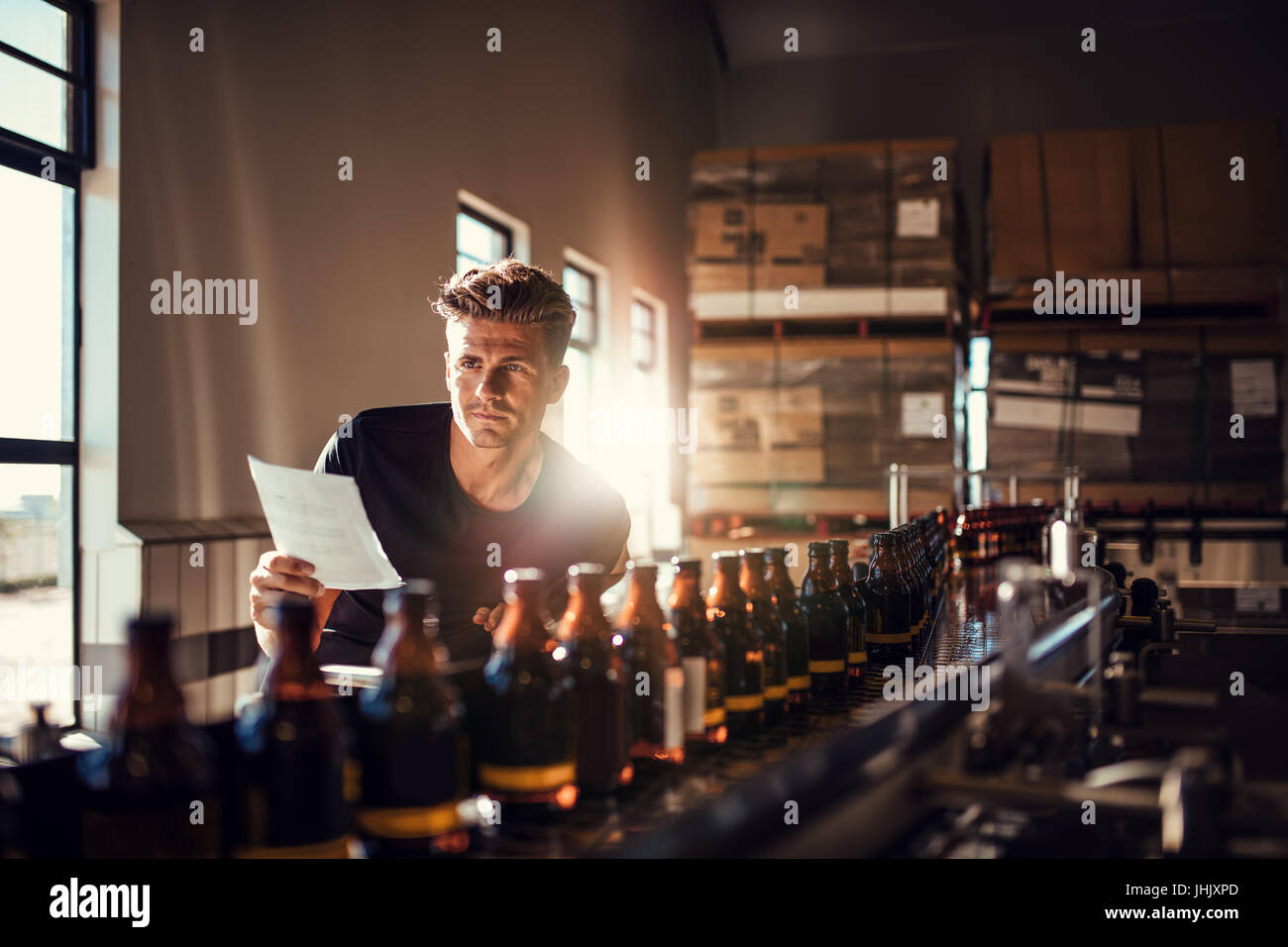 Young man supervising the process of beer manufacturing on brewery ...