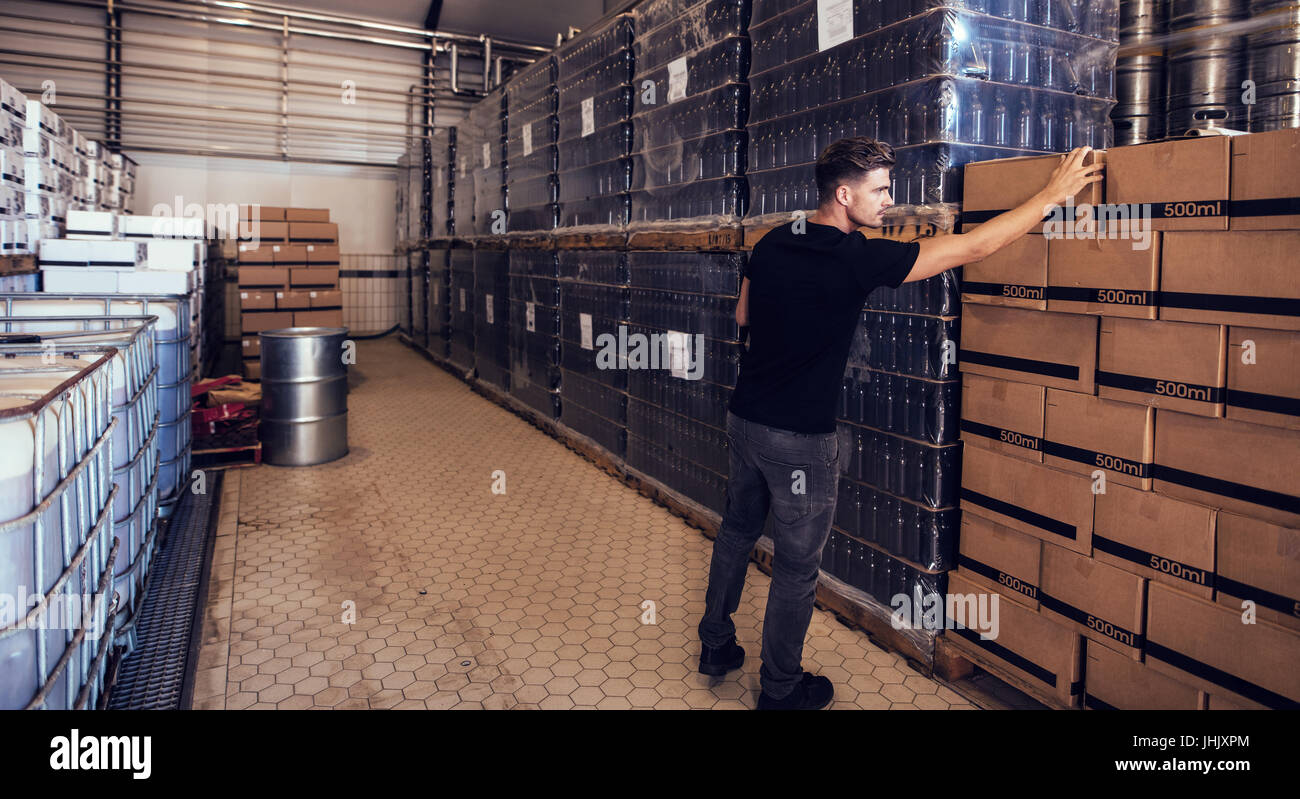 Young businessman looking at the packaged beer boxes in warehouse ...