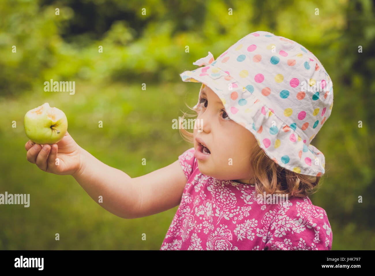 Cute little girl eating freshly picked apple Stock Photo - Alamy