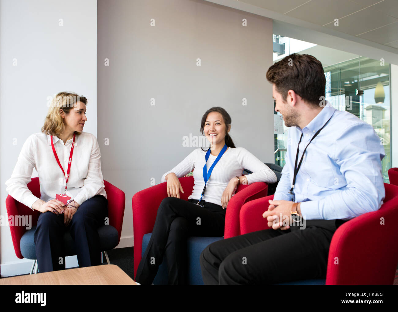 Three office people sitting chatting Stock Photo - Alamy