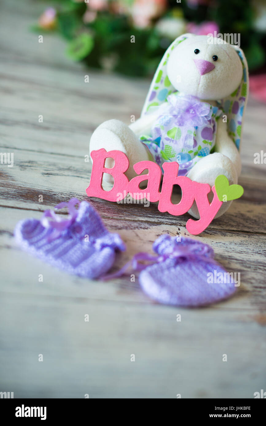 Purple knitted baby socks with an inscription of a child and a toy hare ...