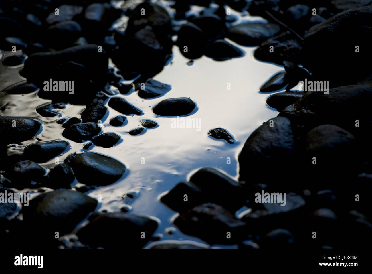 Pool of water with rocks under a darkened overhang Stock Photo - Alamy