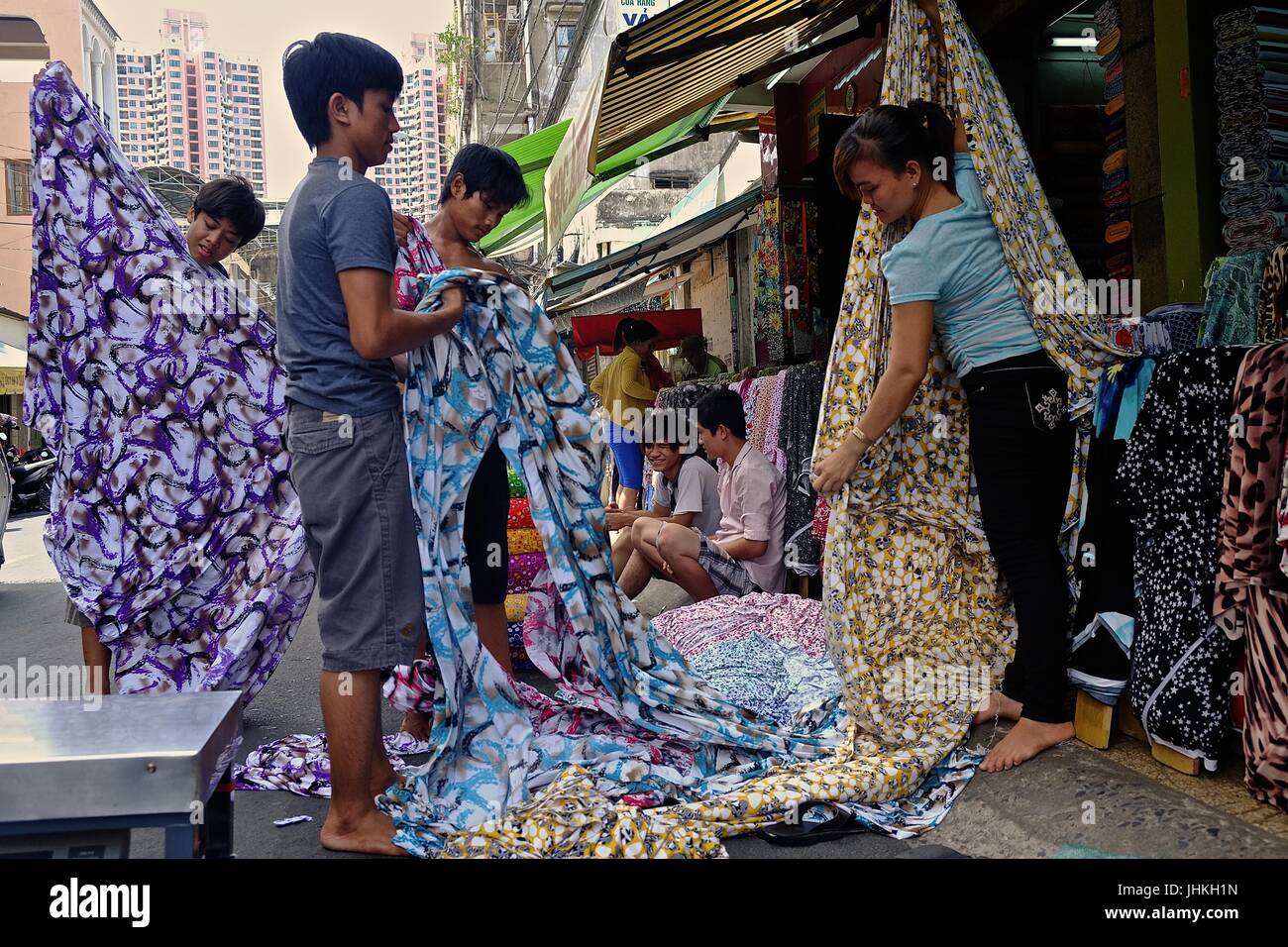 Textile Workers fold cloth at their market stall in Cho Lon, Ho Chi ...